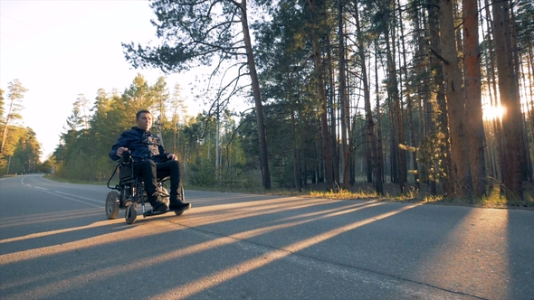 Paraplegic Man Is Moving Along the Road on His Powered Wheelchair in ...
