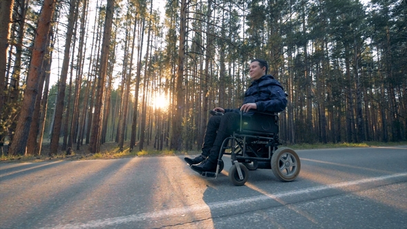 Disabled Man Is Slowly Moving on His Powered Wheelchair Along the Alley ...