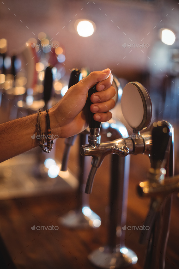 Bartender hands using beer tap in pub Stock Photo by Wavebreakmedia
