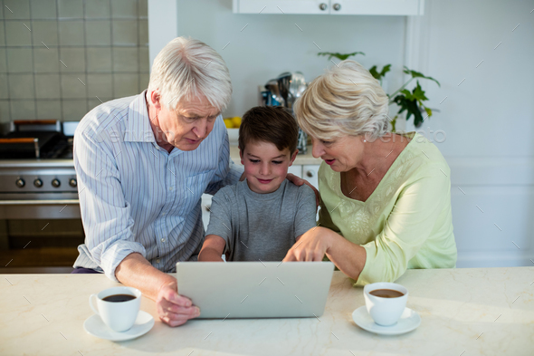 Grandson using laptop with grandparents Stock Photo by Wavebreakmedia