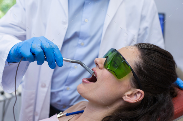 Dentist examining a female patient with dental equipment Stock Photo by ...