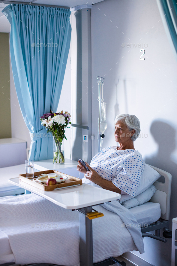 Female senior patient using mobile phone on bed Stock Photo by ...