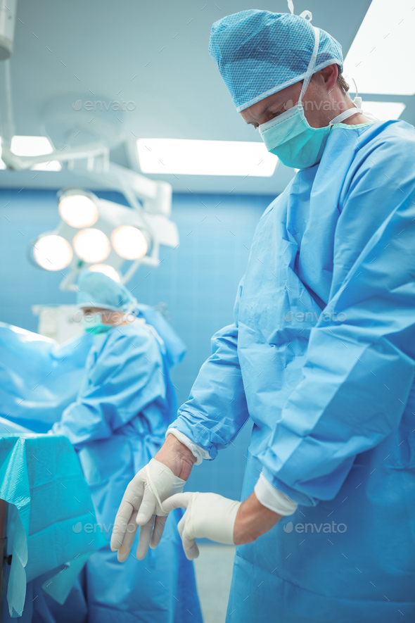 Male surgeon wearing surgical gloves in operation theater Stock Photo ...