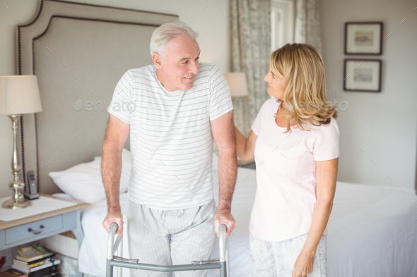 Senior woman helping man to walk with walker Stock Photo by Wavebreakmedia
