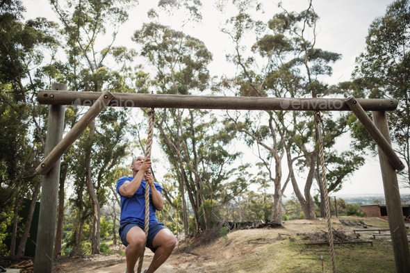 Fit man climbing down the rope during obstacle course Stock Photo by ...