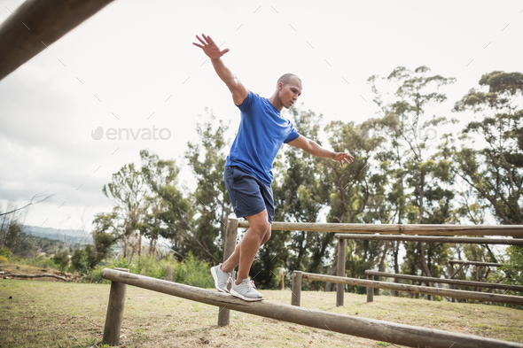 Fit man balancing on hurdles during obstacle course training Stock ...