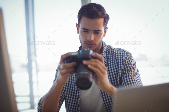 Photo editor holding camera while sitting in office Stock Photo by ...