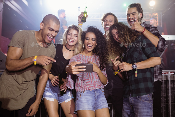 Cheerful friends looking at mobile phone in nightclub Stock Photo by ...