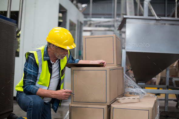 Male factory worker counting cardboard boxes Stock Photo by Wavebreakmedia