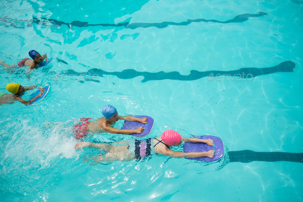 Girls and boys using kickboard while swimming in pool Stock Photo by ...
