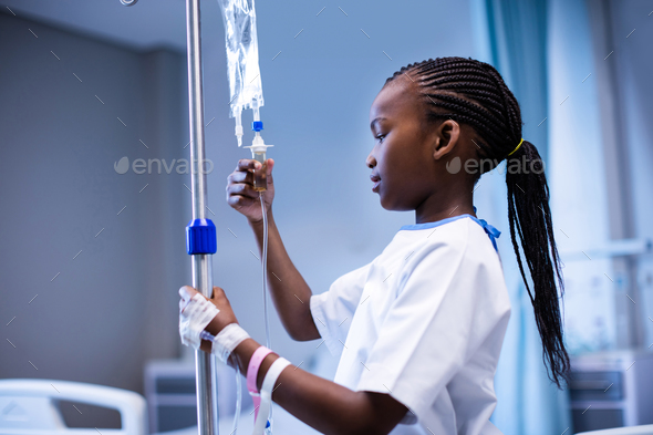 Patient holding IV stand at hospital Stock Photo by Wavebreakmedia