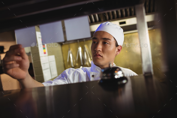 Chef looking at an order list in the commercial kitchen Stock Photo by ...