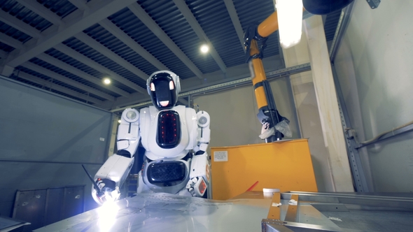 Metal Plate Is Being Welded By a Cyborg in a Modern Factory Facility ...