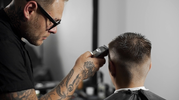 Tattoed Barber Makes Haircut for Customer at the Barber Shop By Using ...