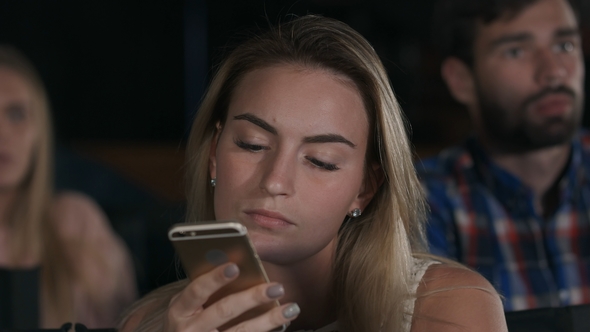 Shot of a Beautiful Young Female Texting During Movies at the Local ...