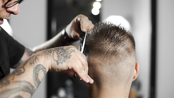 Tattoed Barber Makes Haircut for Customer at the Barber Shop By Using ...