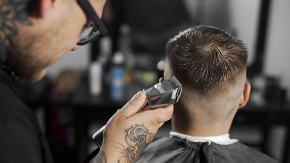 Tattoed Barber Makes Haircut for Customer at the Barber Shop By Using ...