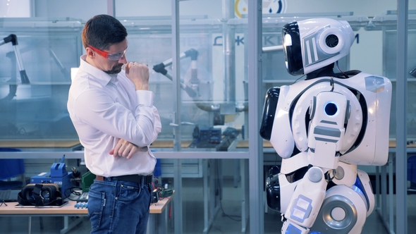 A Man Pushes a Cyborg Twice. Male Worker Test Robot's Balance, Pushing ...