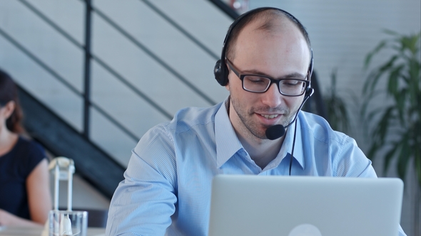 Joyful Call Centre Agent with His Headset Talking Looking at Laptop ...