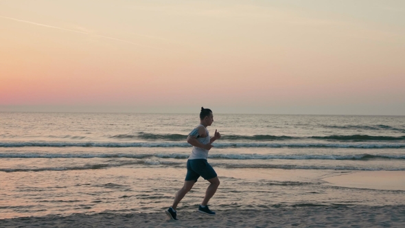 Sporty Man Is Jogging on Beach and Running Along Ocean Coast at Sunset ...
