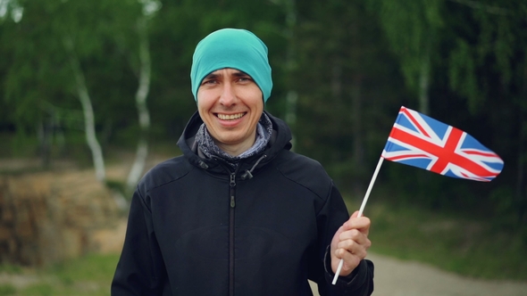 Portrait of Smiling Englishman Sports Fan Holding UK Flag Flying in the ...