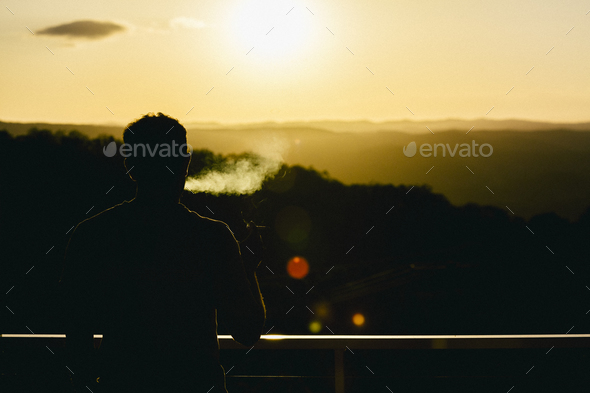 Man smoking watching the sun set Stock Photo by ImageSupply | PhotoDune