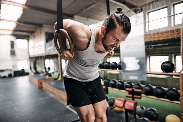 Fit young man hanging from rings during a gym workout Stock Photo by ...