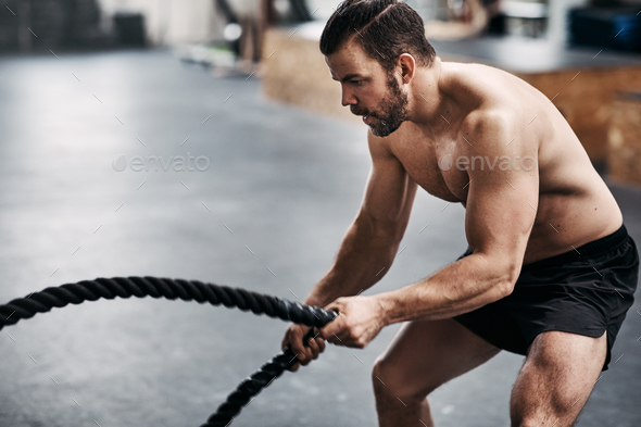 Fit young man swinging ropes during a gym workout Stock Photo by ...