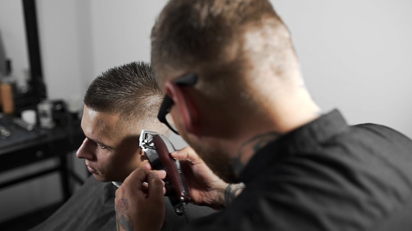 Tattoed Barber Makes Haircut for Customer at the Barber Shop By Using ...