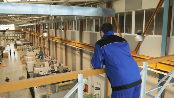 A Supervisor or Worker Overlooks Production of a Large Factory, Stock ...