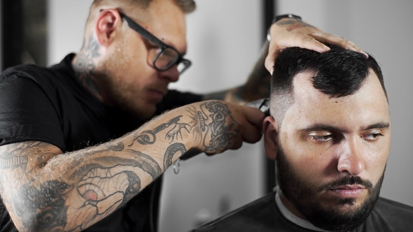 Tattoed Barber Makes Haircut for Customer at the Barber Shop By Using ...