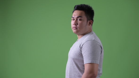 Young Handsome Overweight Asian Man Against Green Background, Stock Footage
