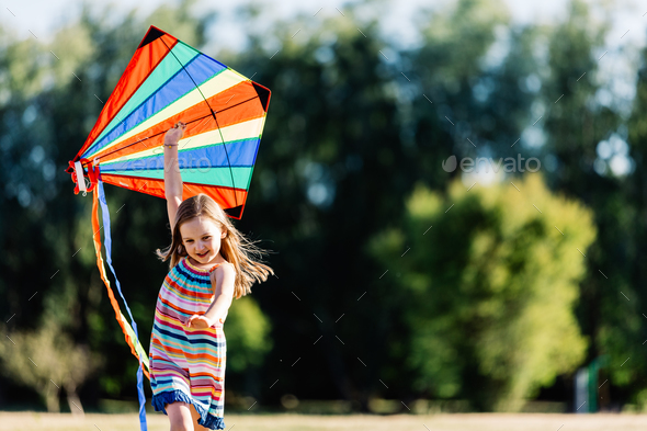 Smiling little girl playing with a colorful kite in the park. Stock ...