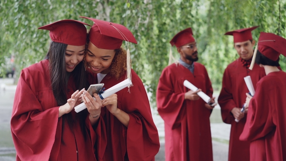 Attractive Young Women Happy Graduates Are Watching Photos on Smart ...