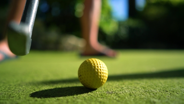 Mini Golf Yellow Ball with a Bat Near the Hole at Sunset, Stock Footage