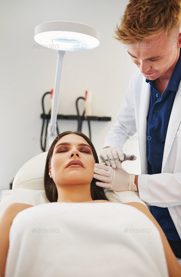 Young male doctor performing botox injections on a female client Stock ...
