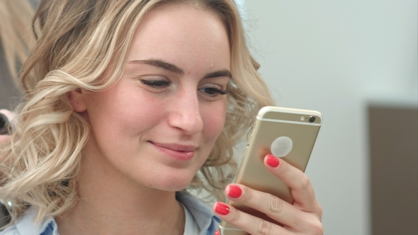 Beautiful Woman Using Smartphone in a Beauty Salon, While Having a Hair ...