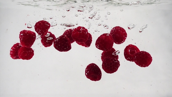 A Beautiful Raspberry Falls Into the Water with Bubbles in, Stock Footage