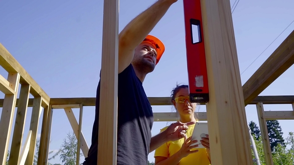 Man and Woman Builders Are Measuring Level of Fixed Beams in a Wooden ...