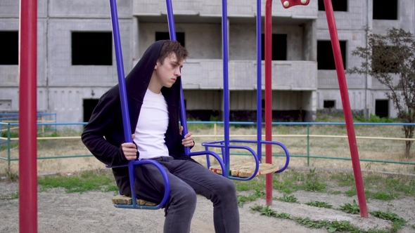 Young Man in a Poor State of Health Sits on a Swing, Stock Footage