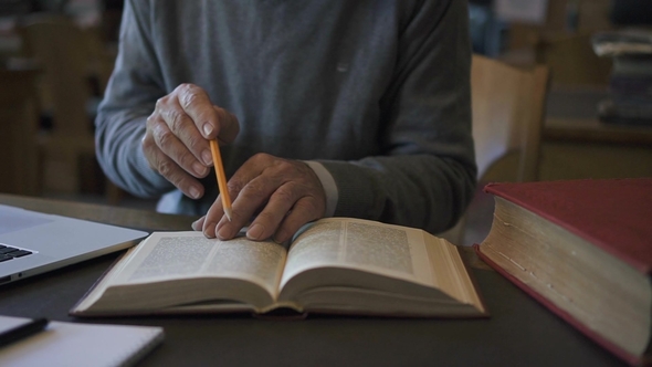Elderly Male Biologist Professor Is Examining Book Sitting at Table in ...