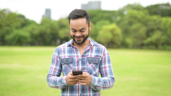 Young Handsome Indian Man In Park Using Mobile Phone, Stock Footage