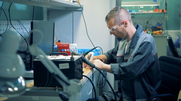 Workshop with a Male Employee Soldering a Circuit with Artificial Hands ...