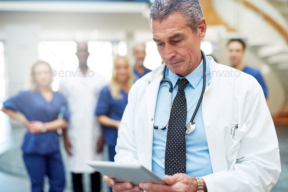 Portrait of doctor with tablet in clinic Stock Photo by FlamingoImages