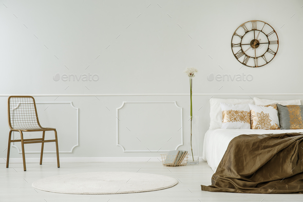 Gold clock above bed with blanket in white bedroom interior with Stock ...
