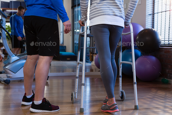 Physiotherapist assisting patient to walk with walking frame Stock ...