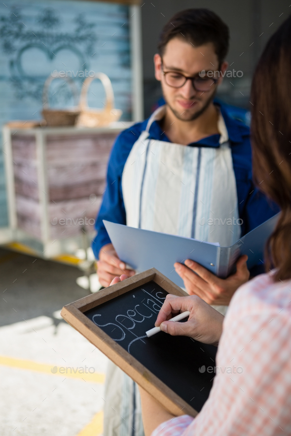 Woman writing menu while coworker reading document Stock Photo by ...