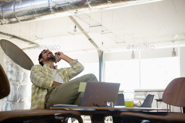 Man looking up while talking on phone in office Stock Photo by ...