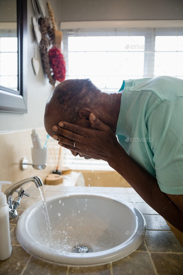 Side view of senior man washing his face at sink Stock Photo by ...