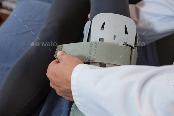 Physiotherapist tying leg pad Stock Photo by Wavebreakmedia | PhotoDune